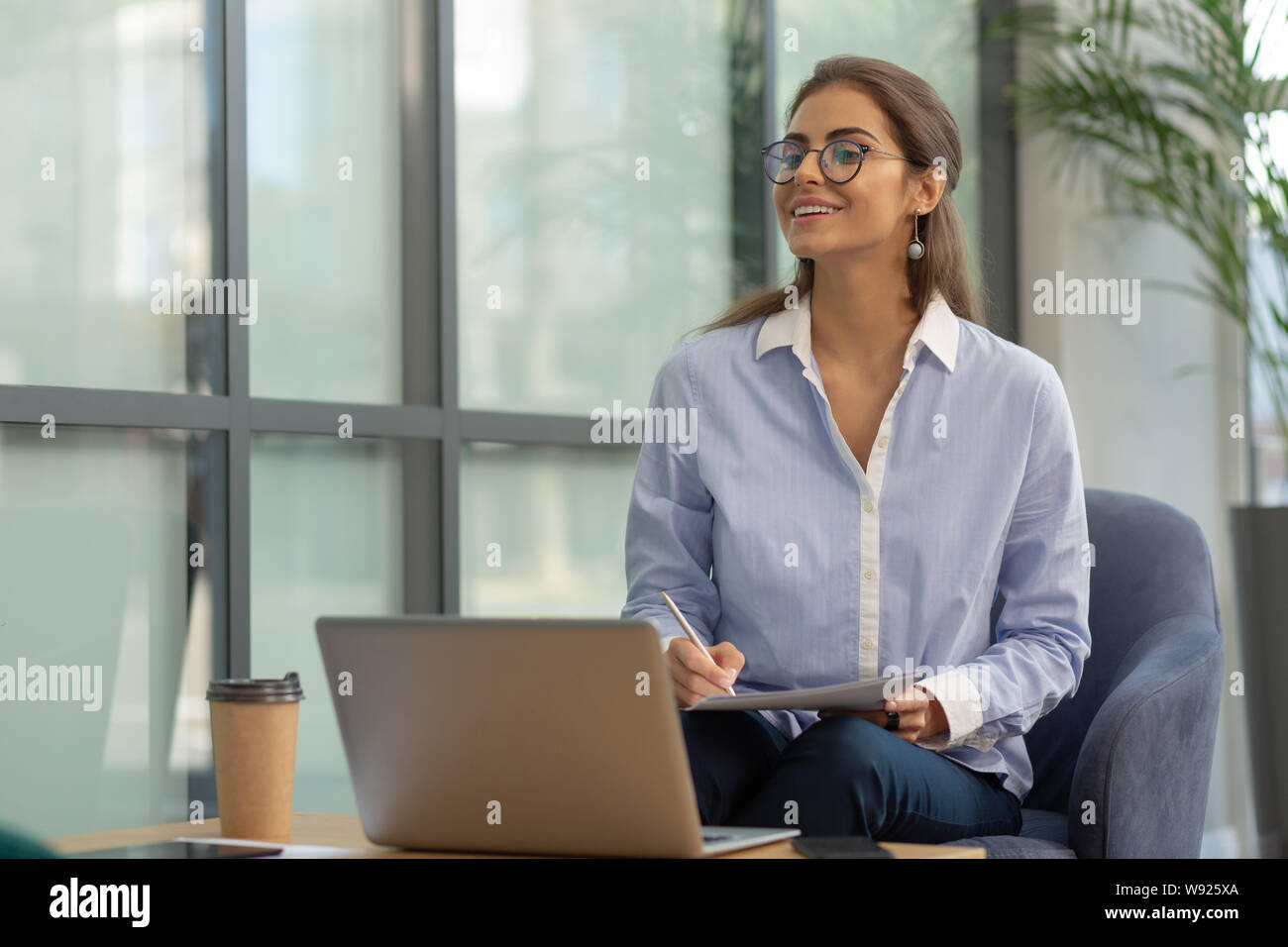 Positive delighted longhaired female person making notes Stock Photo ...