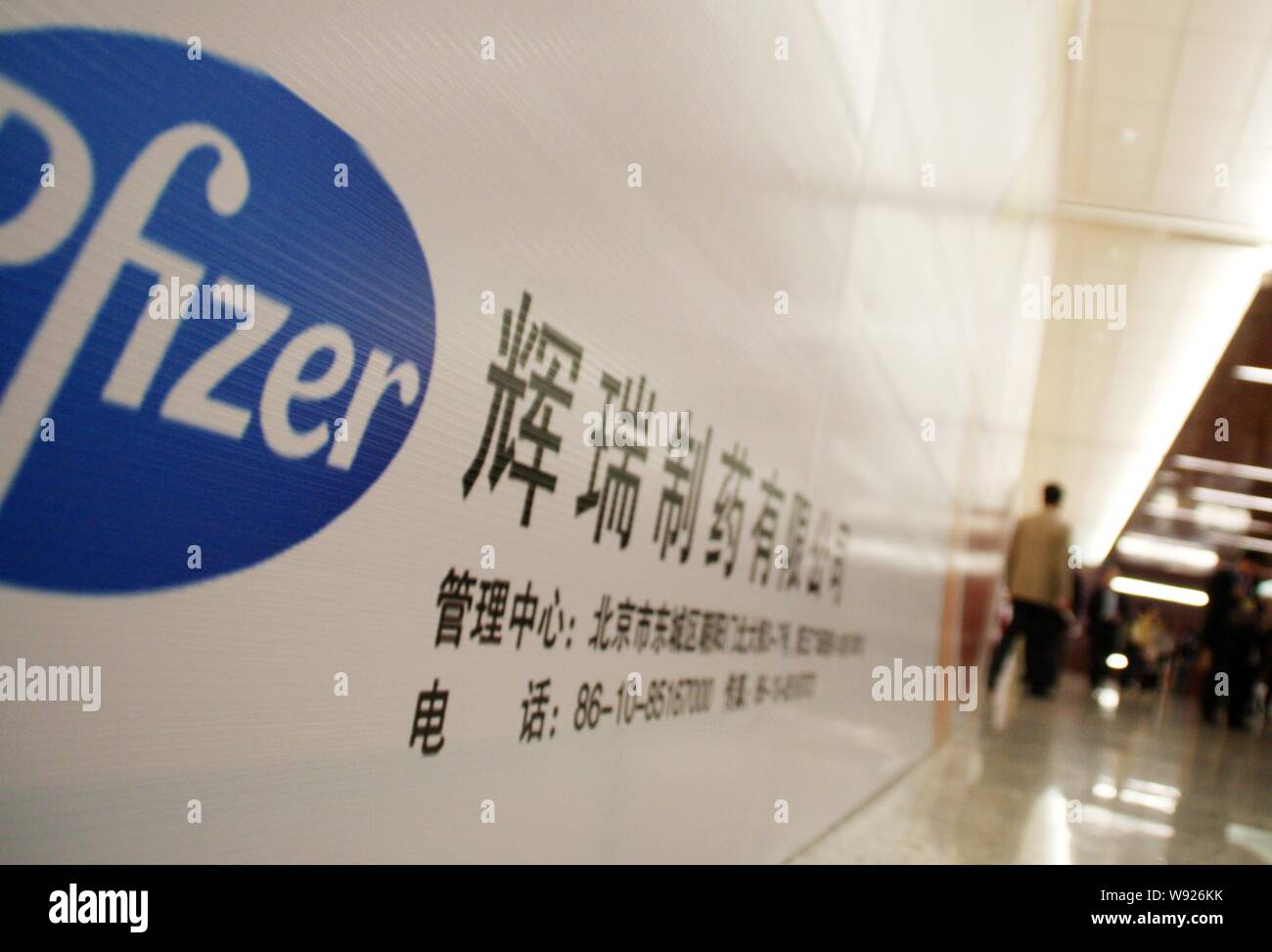 People walk past an advertisement for Pfizer during a conference in ...