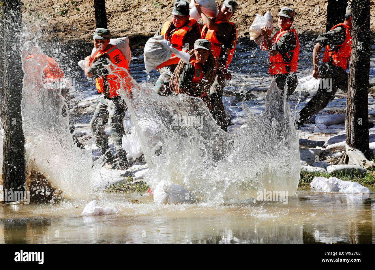 Chinese paramilitary policemen throw sandbags into the water to build a ...