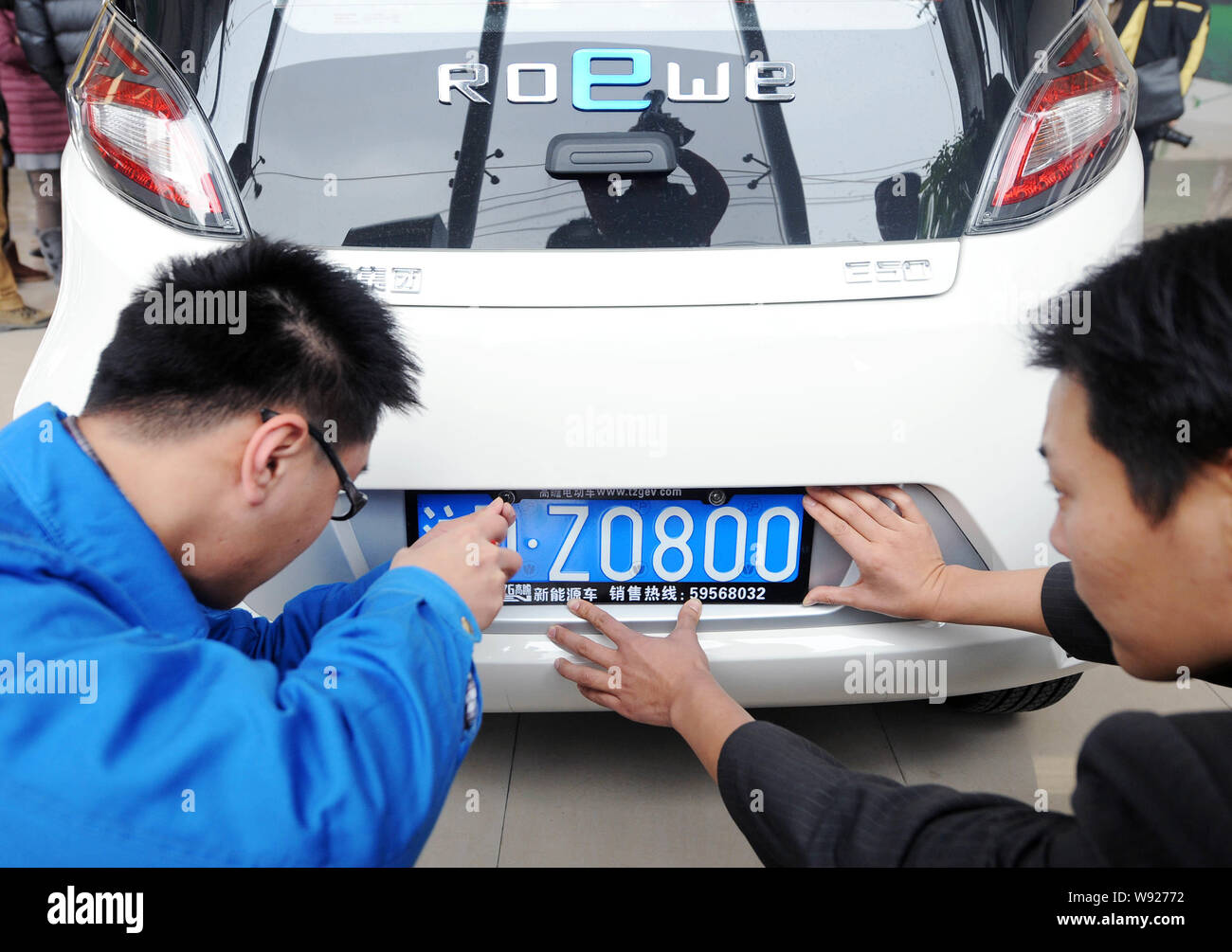 Chinese workers install the first free car plate for new energy ...