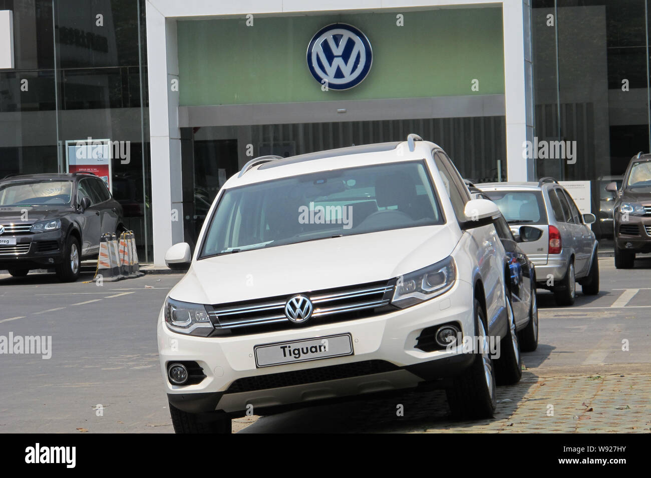 A Tiguan and other Volkswagen cars are parked outside a dealership of ...