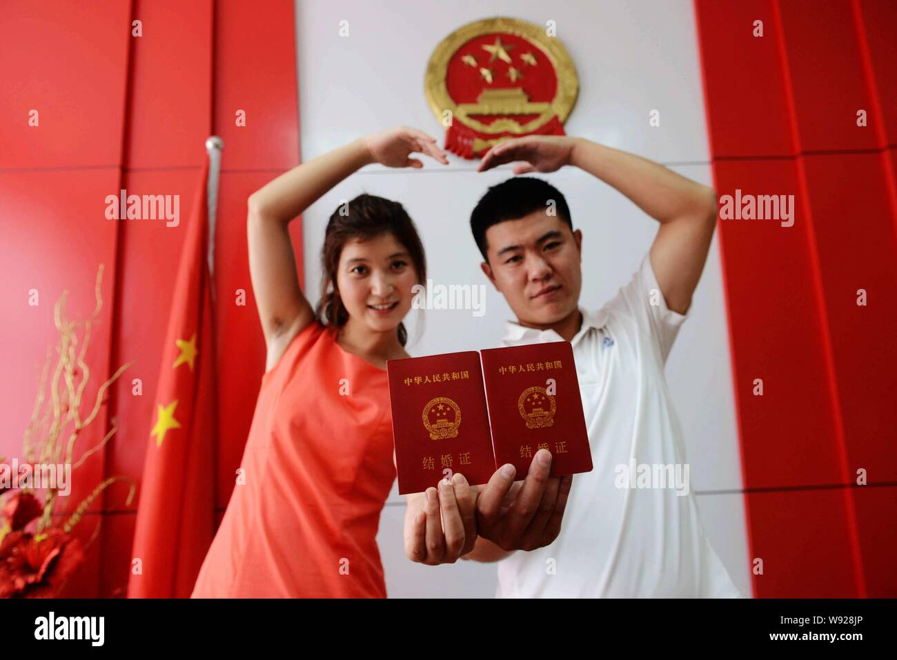 A young Chinese couple poses as they show their marriage certificates ...