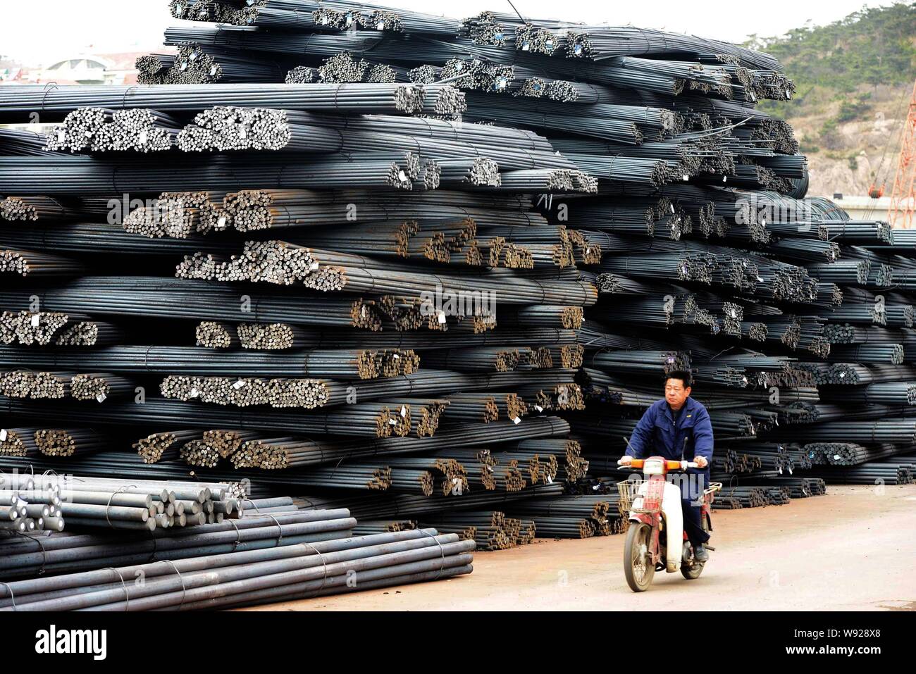 --FILE--A Chinese man cycles past a stack of reinforcing steel rods at ...