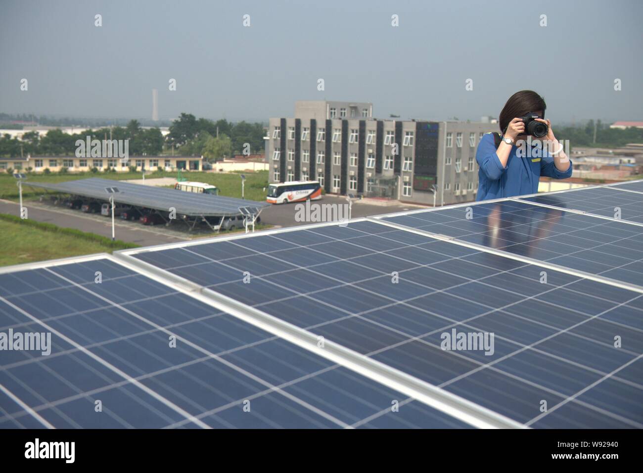 A Chinese visitor takes photos of solar panels at the rooftop of a ...