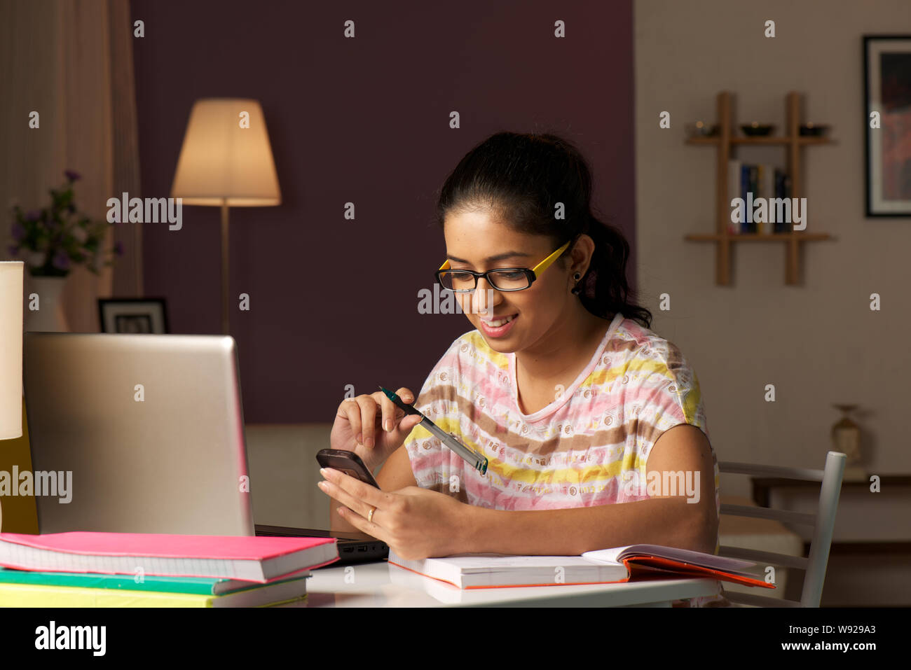 Teenage girl text messaging while studying at home Stock Photo - Alamy