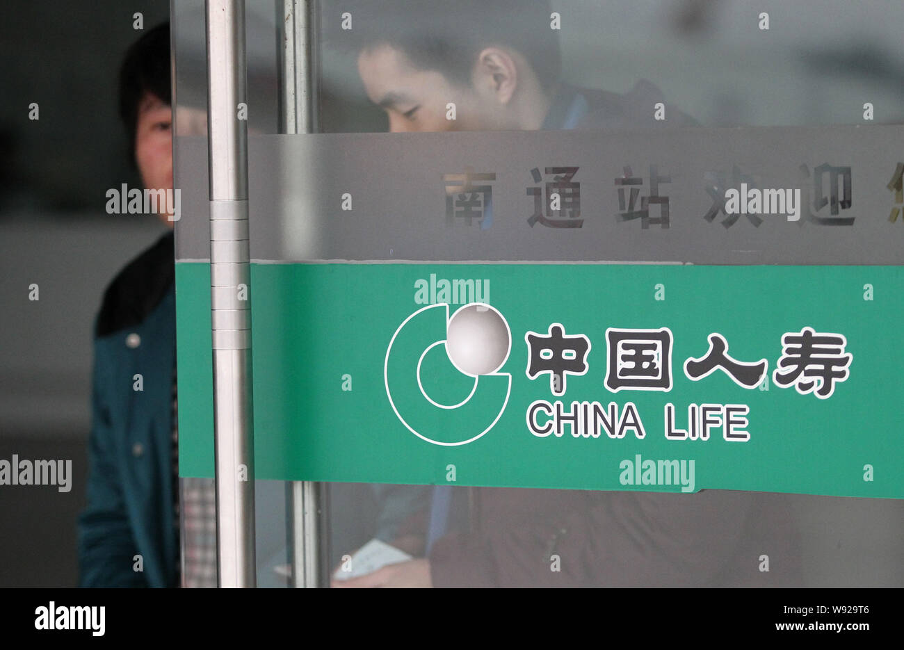 --FILE--Chinese passengers walk past an advertisements of China Life ...