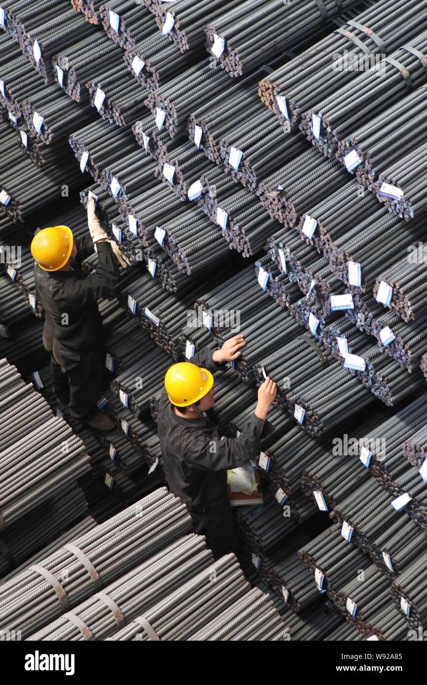 Chinese workers examine a stack of reinforcing steel rods to be ...