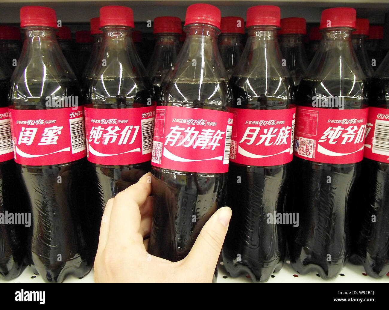 A customer picks a bottle of Coca-Cola with new packaging from the ...