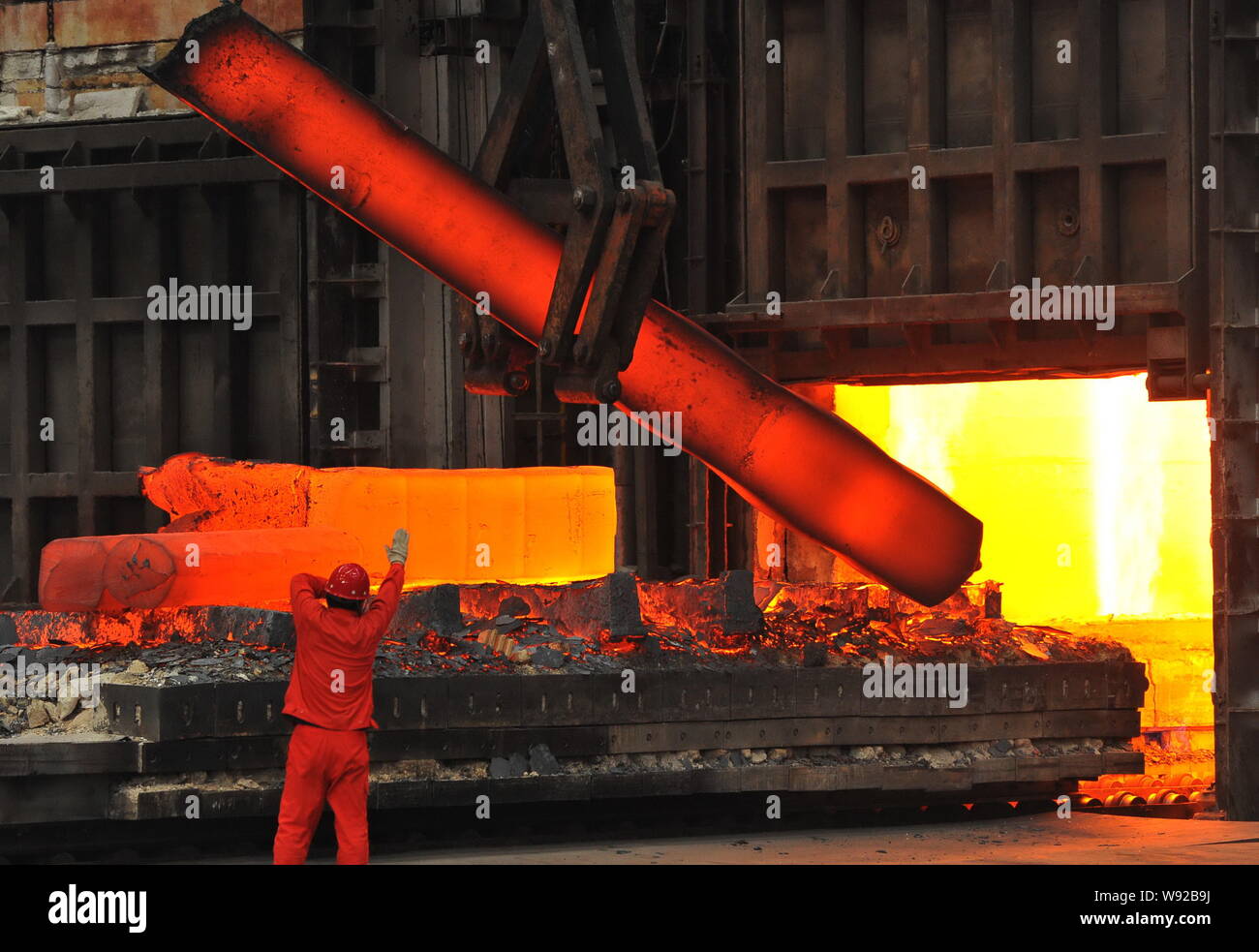 --FILE--A Chinese worker directs a crane to lift steel rods into a ...