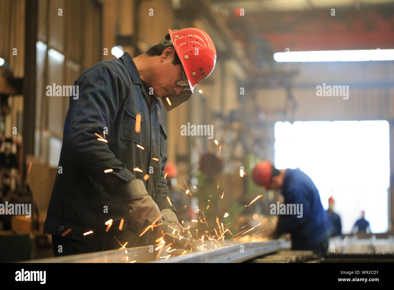 --FILE--Chinese factory workers polish parts of chassises of heavy duty ...