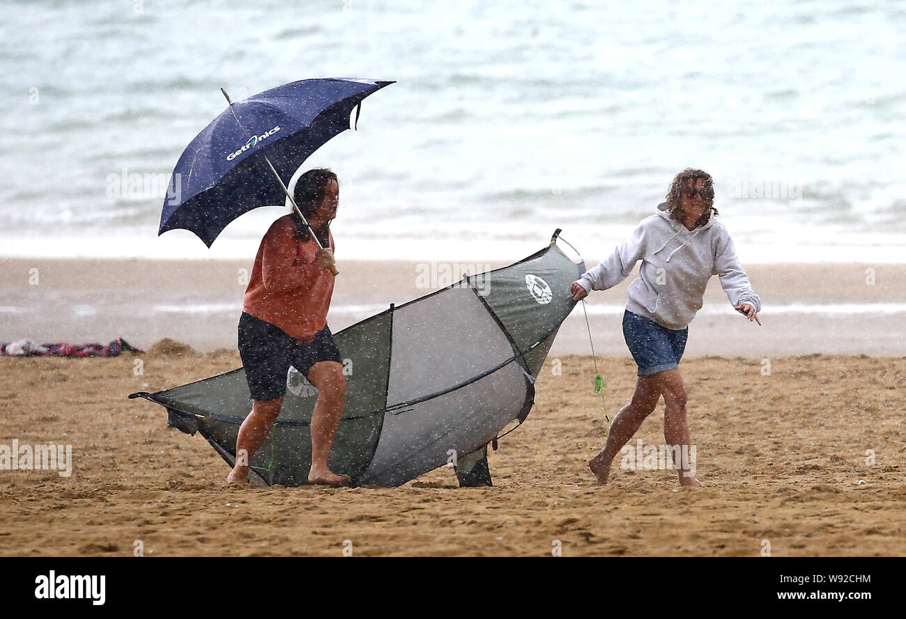 People on the beach in Margate, Kent, during heavy rain as ...