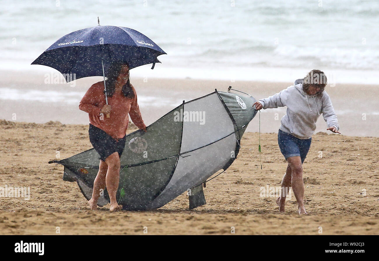 People on the beach in Margate, Kent, during heavy rain as ...
