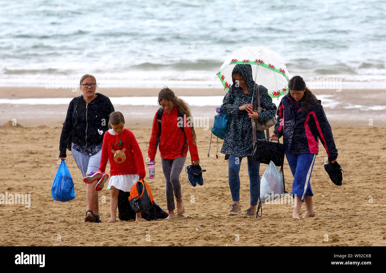 People on the beach in Margate, Kent, during heavy rain as ...