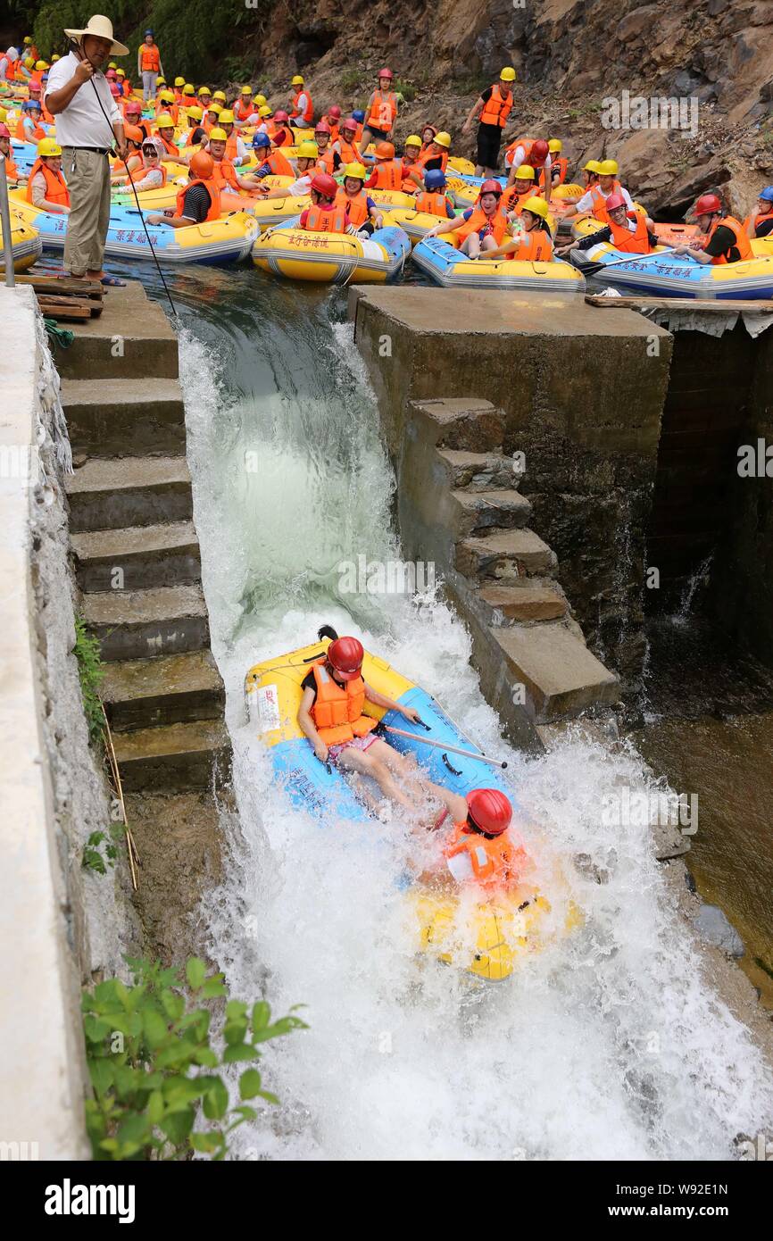 A crowd of holidaymakers sitting in life rafts wait for a waterfall ...