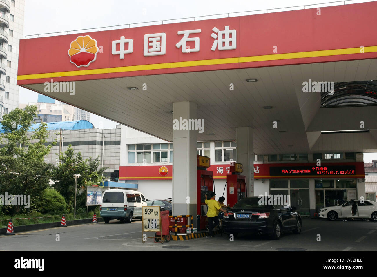 Chinese employees refuel a car at a gas station of CNPC (China National ...