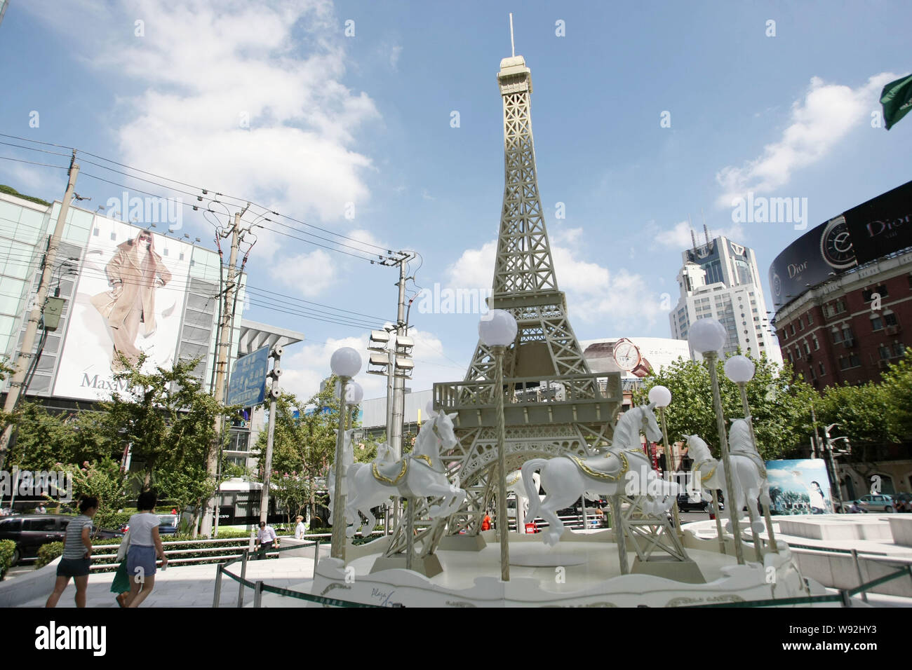 Pedestrians walk past a scale model of Eiffel Tower in front of the ...