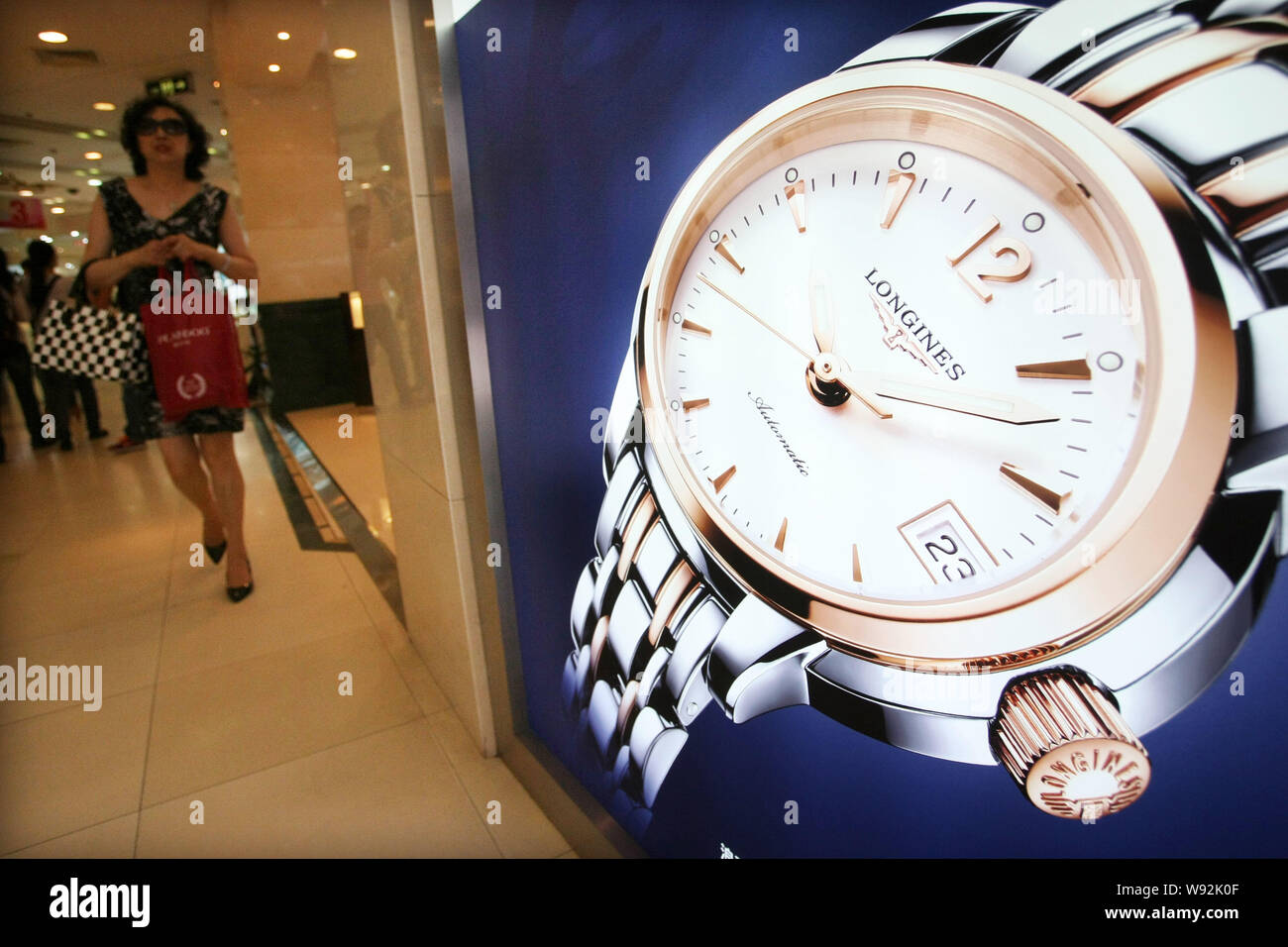 A customer walks past an advertisement for Longines watches at a ...
