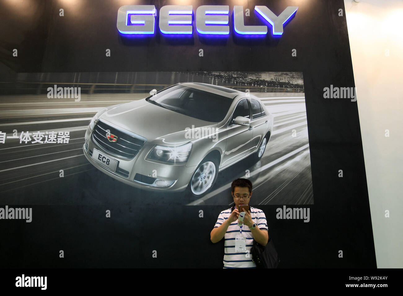 --FILE--A visitor uses his mobile phone in front of the stand of Geely ...