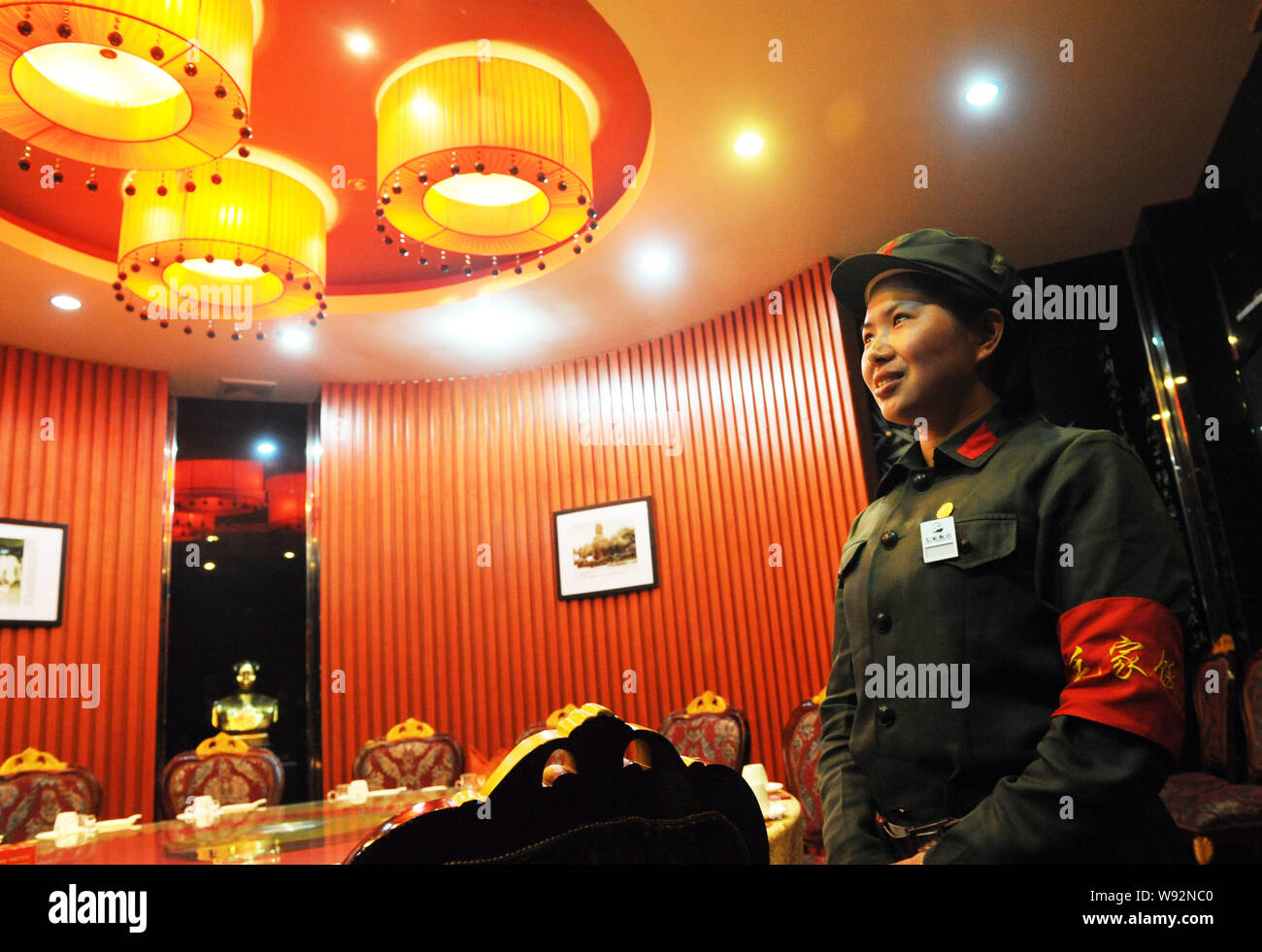 A waitress in red guard uniform stands in a room at the Maos Restaurant ...