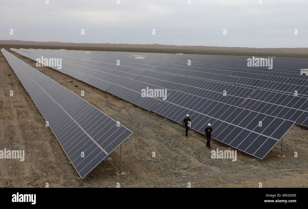 Chinese inspectors walk past arrays of solar panels at a photovoltaic ...