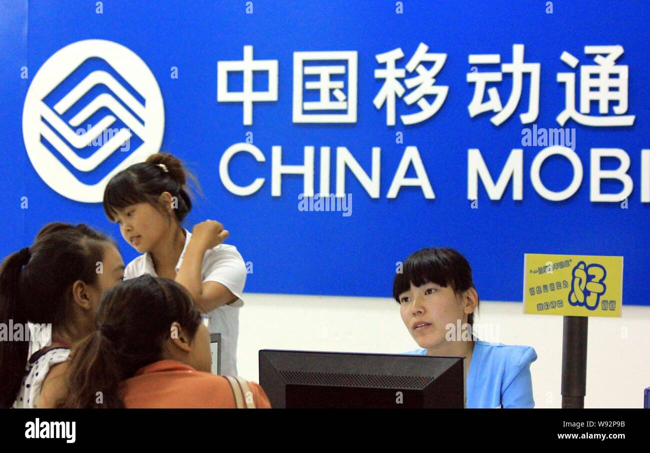 A Chinese employee talks with customers at a branch of China Mobile in ...