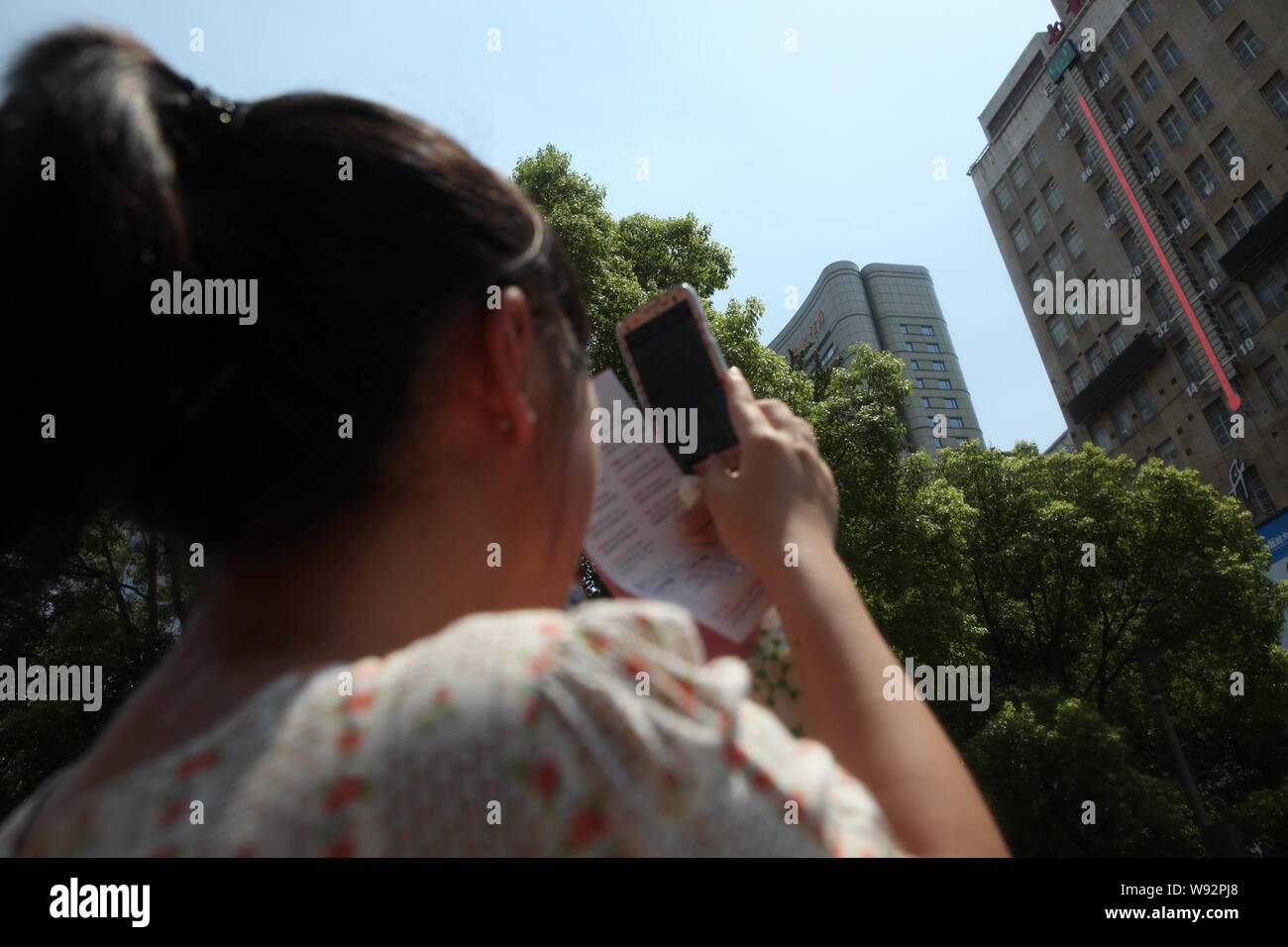 A pedestrian takes photos of a giant thermometer showing the current ...