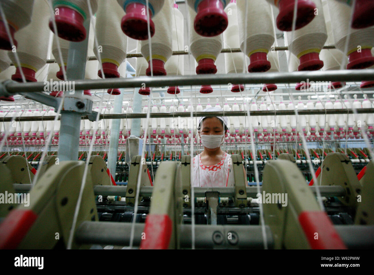A female Chinese worker handles production of yarn to be exported to Southeast Asia on a ...