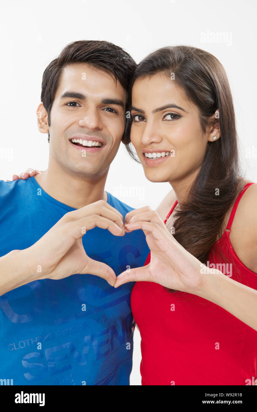 Young couple making heart shape with hands and smiling Stock Photo - Alamy