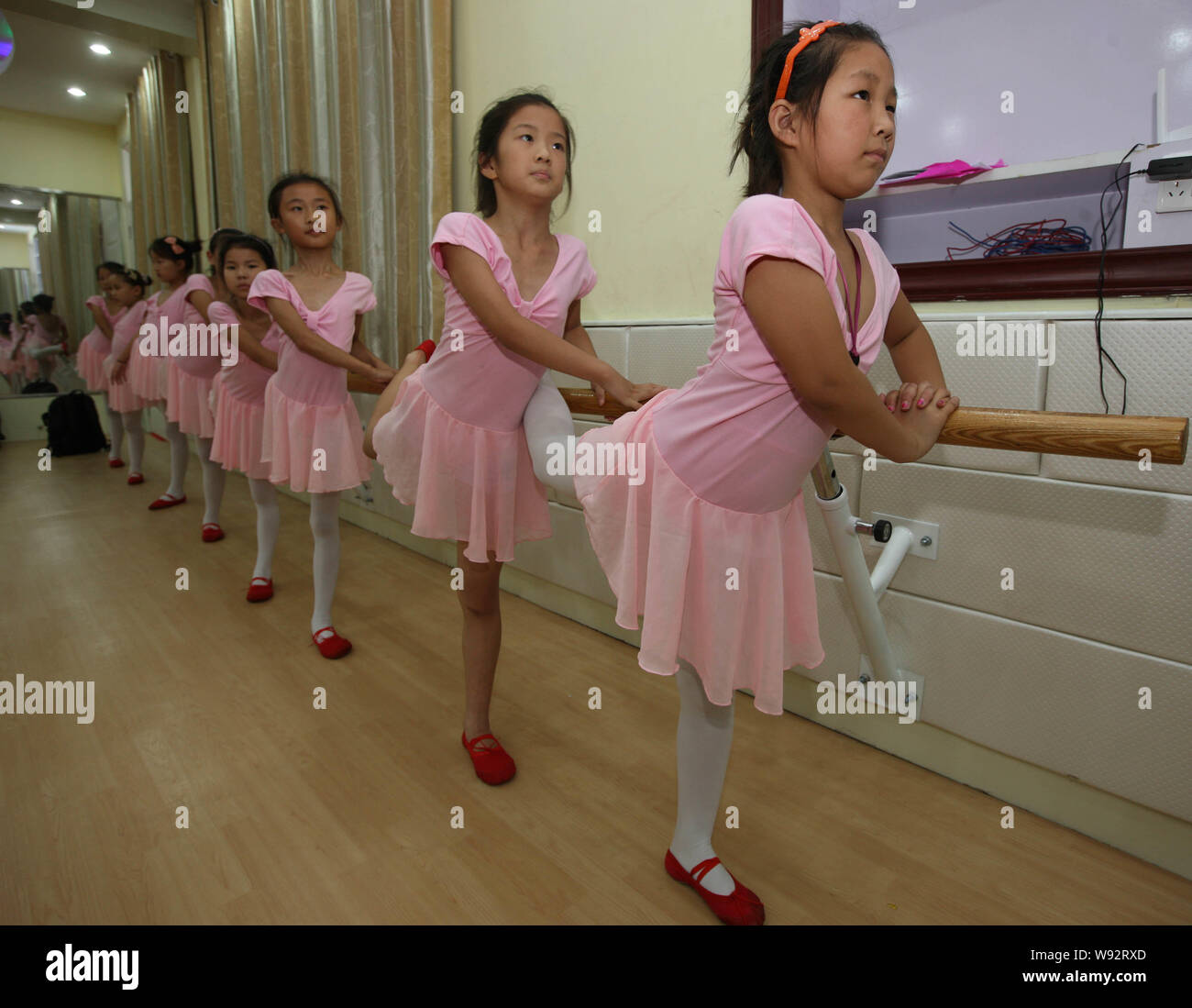 Young Chinese girls stretch their legs backward on a ballet barre to ...
