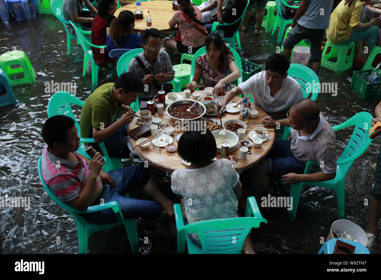 Chinese customers have dinner around a table at a restaurant in a ...