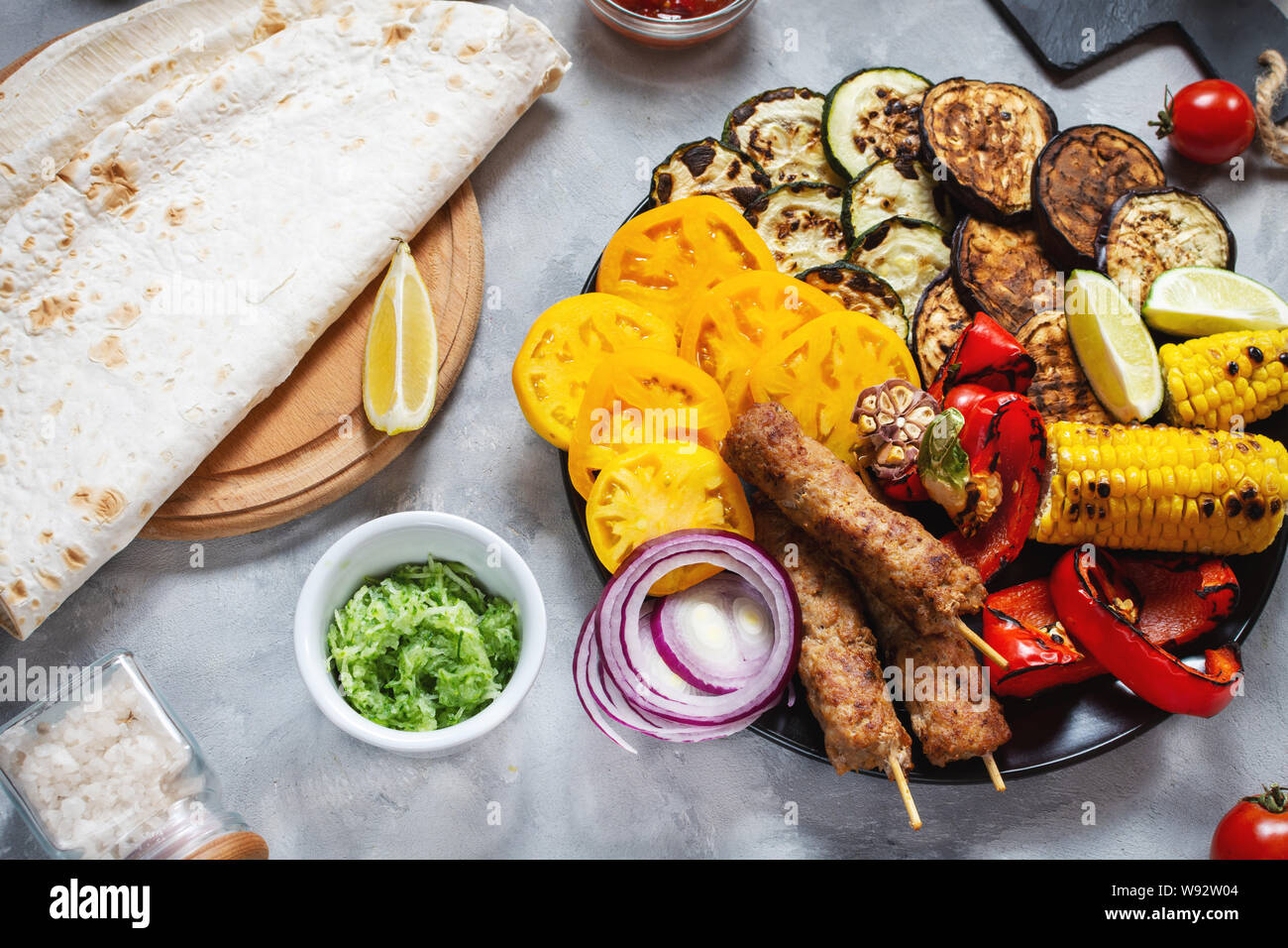 Assorted delicious grilled vegetables and meat on a concrete background ...