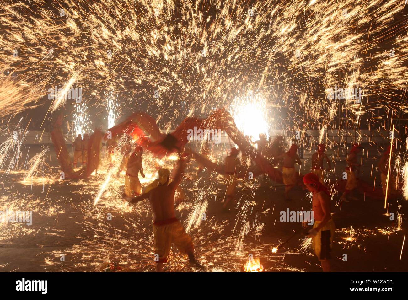 Dancers perform a fire dragon dance in a shower of molten iron during a ...