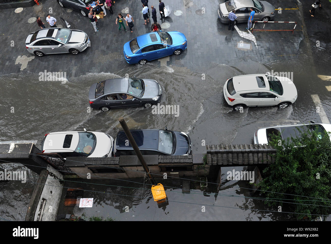 Half-submerged cars travel on a flooded street caused by typhoon Fitow ...
