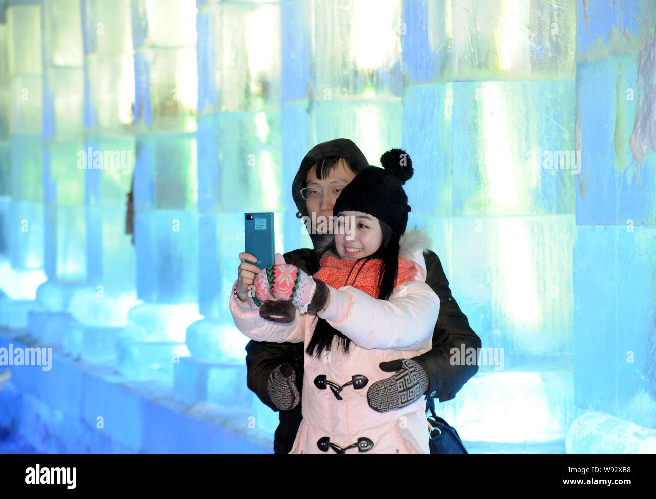 A young couple takes selfies in front of ice sculptures at the 15th ...