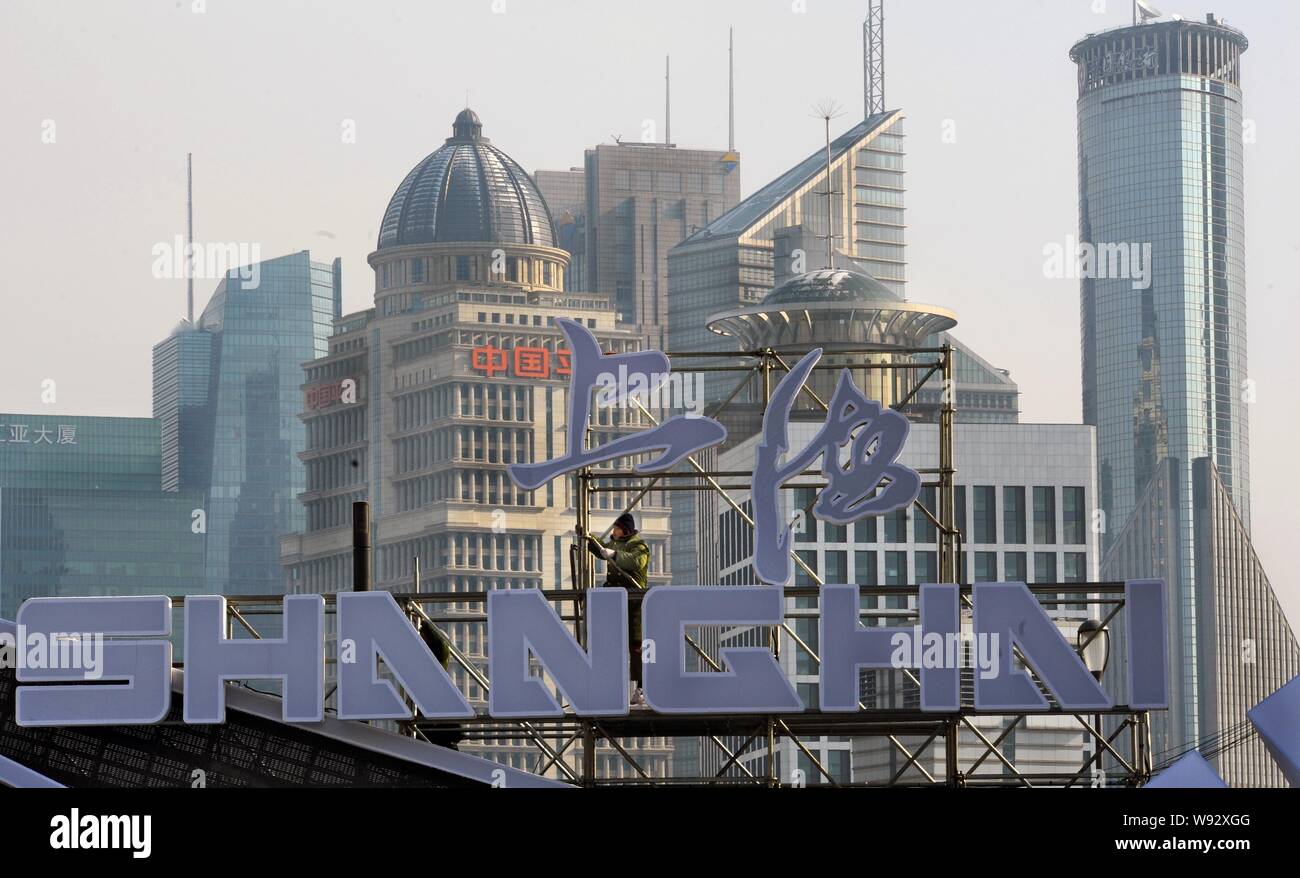 --FILE--Chinese workers install a sign of Shanghai on the Bund against ...