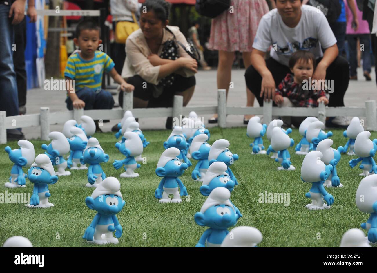 Visitors look at figures of The Smurfs during an exhibition to ...