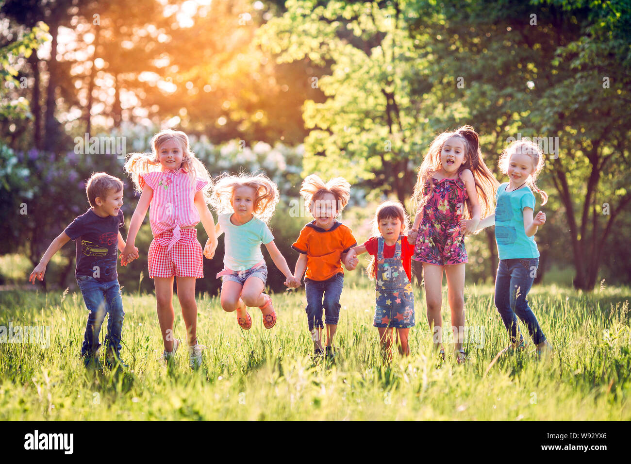 Group of friends running happily together in the grass and jumping ...