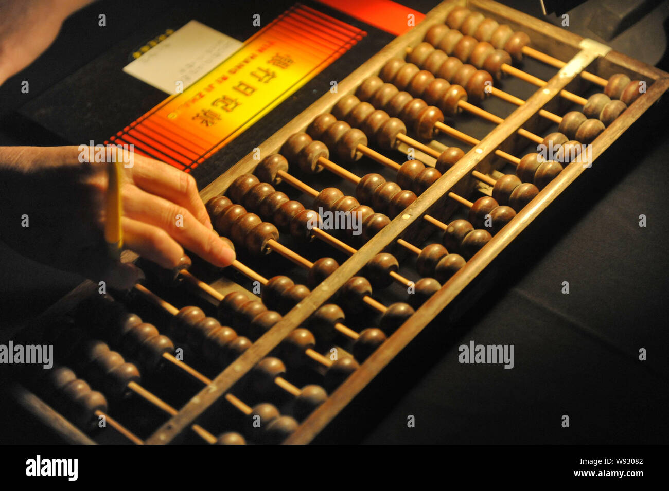 A local Chinese resident calculates on an abacus in Qionghai city ...