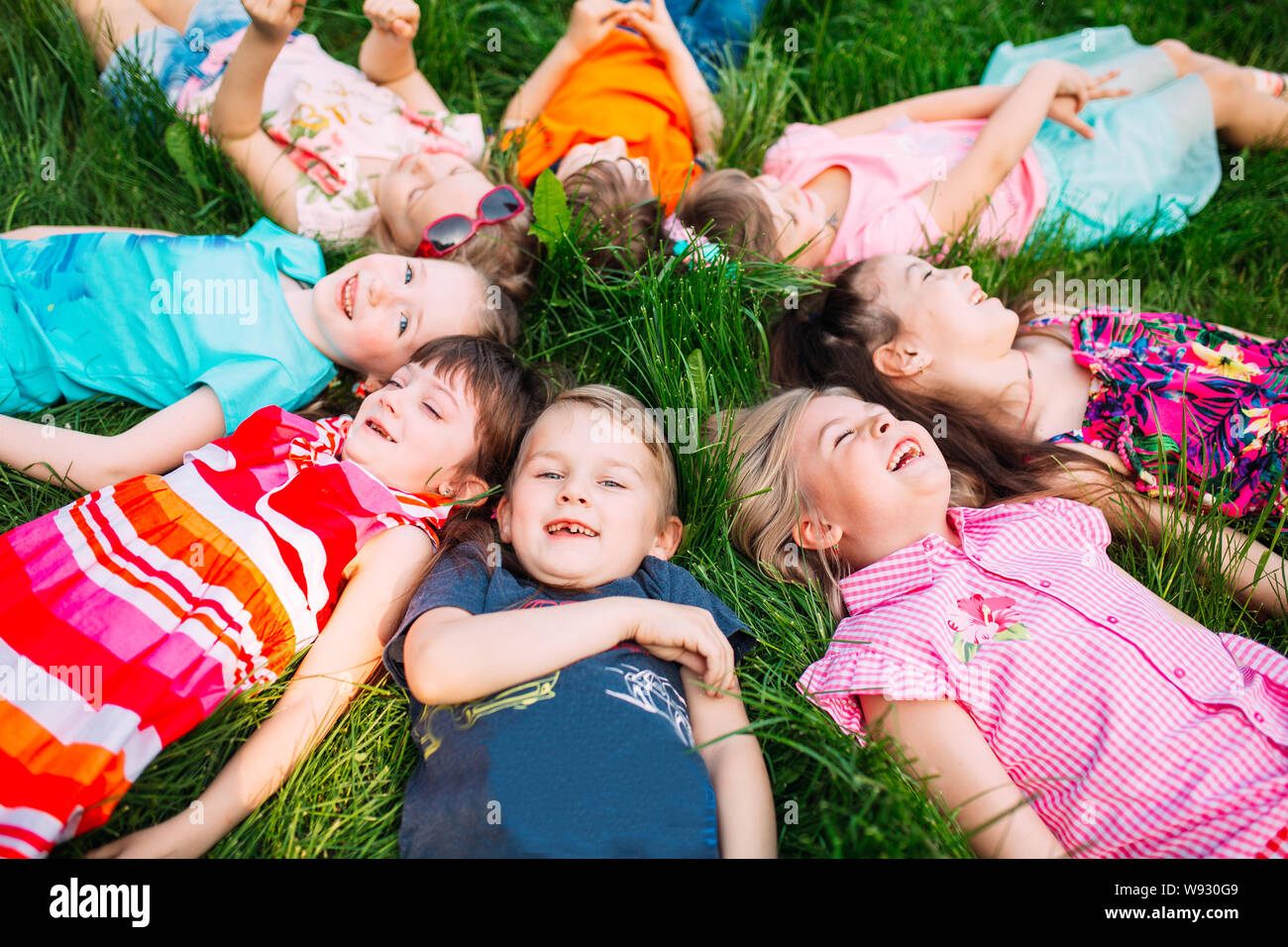 A group of children lying on the green grass in the Park. The ...