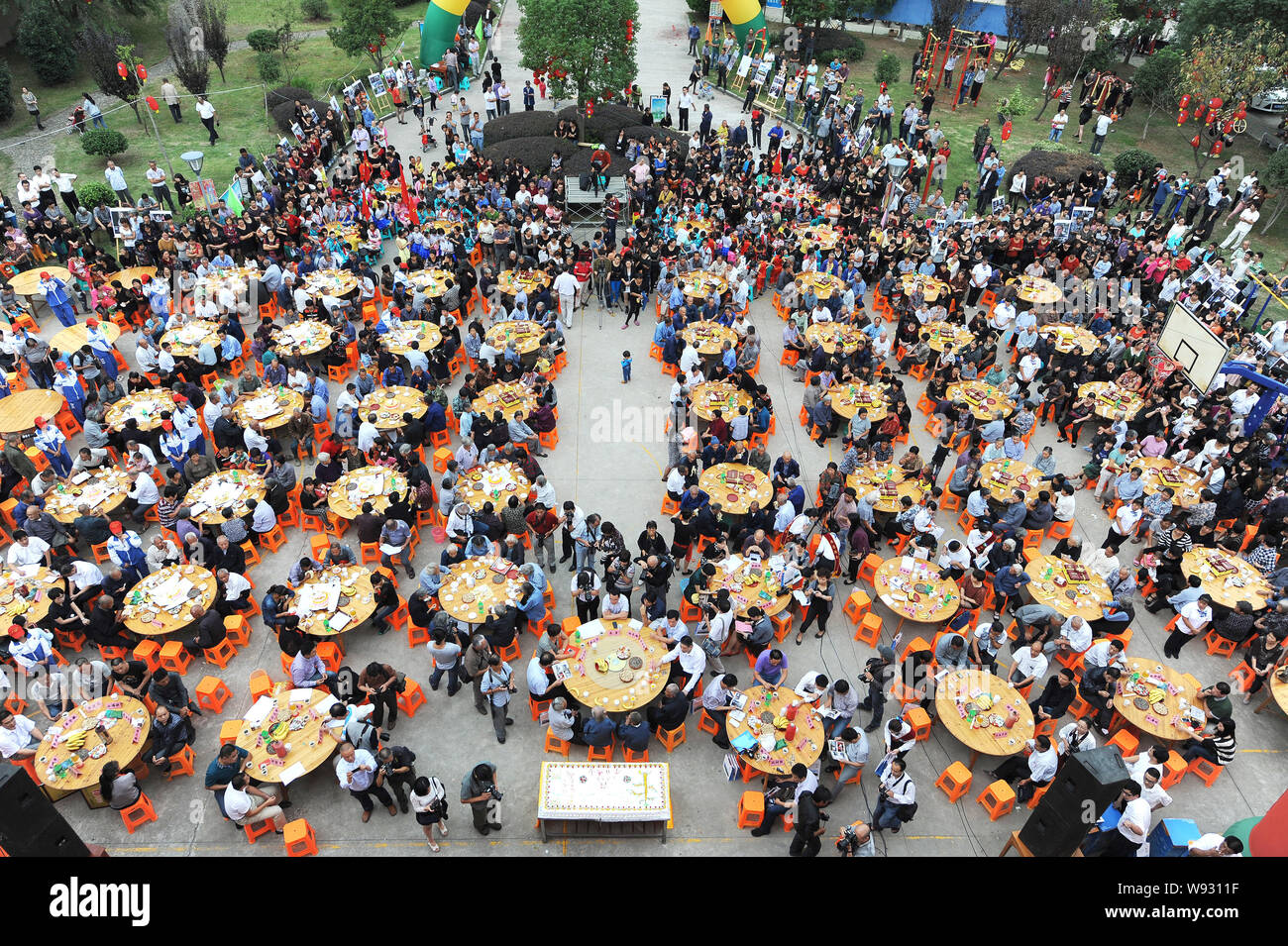 Local elderly people eat cakes and other food around tables at a ...