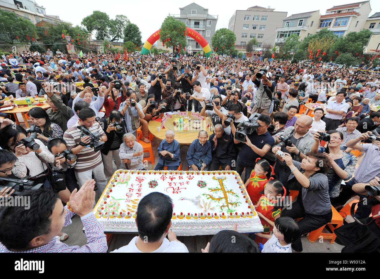 Local villagers take photos and videos of a big cake at a collective ...