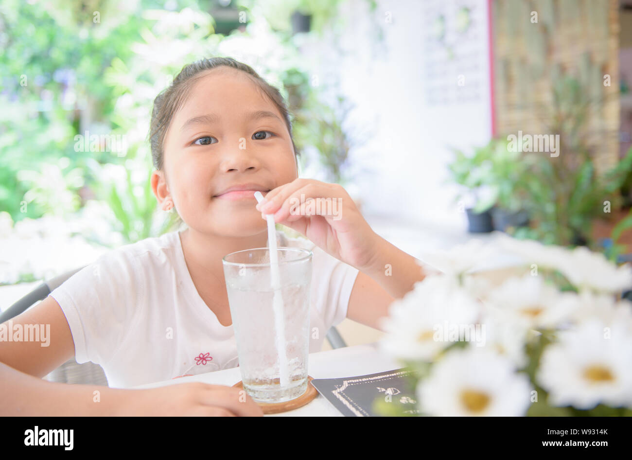 Cate Asian girl drinking glass of water with ice in a restaurant ...