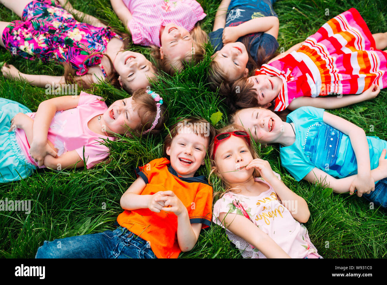 A group of children lying on the green grass in the Park. The ...