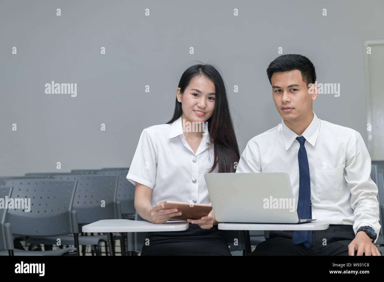 Students in uniform working and reading in classroom in university ...