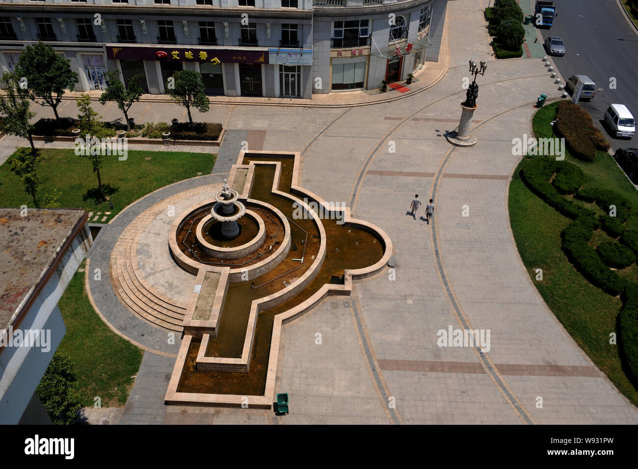 Pedestrians walk past a fountain in front of Parisian-style ...