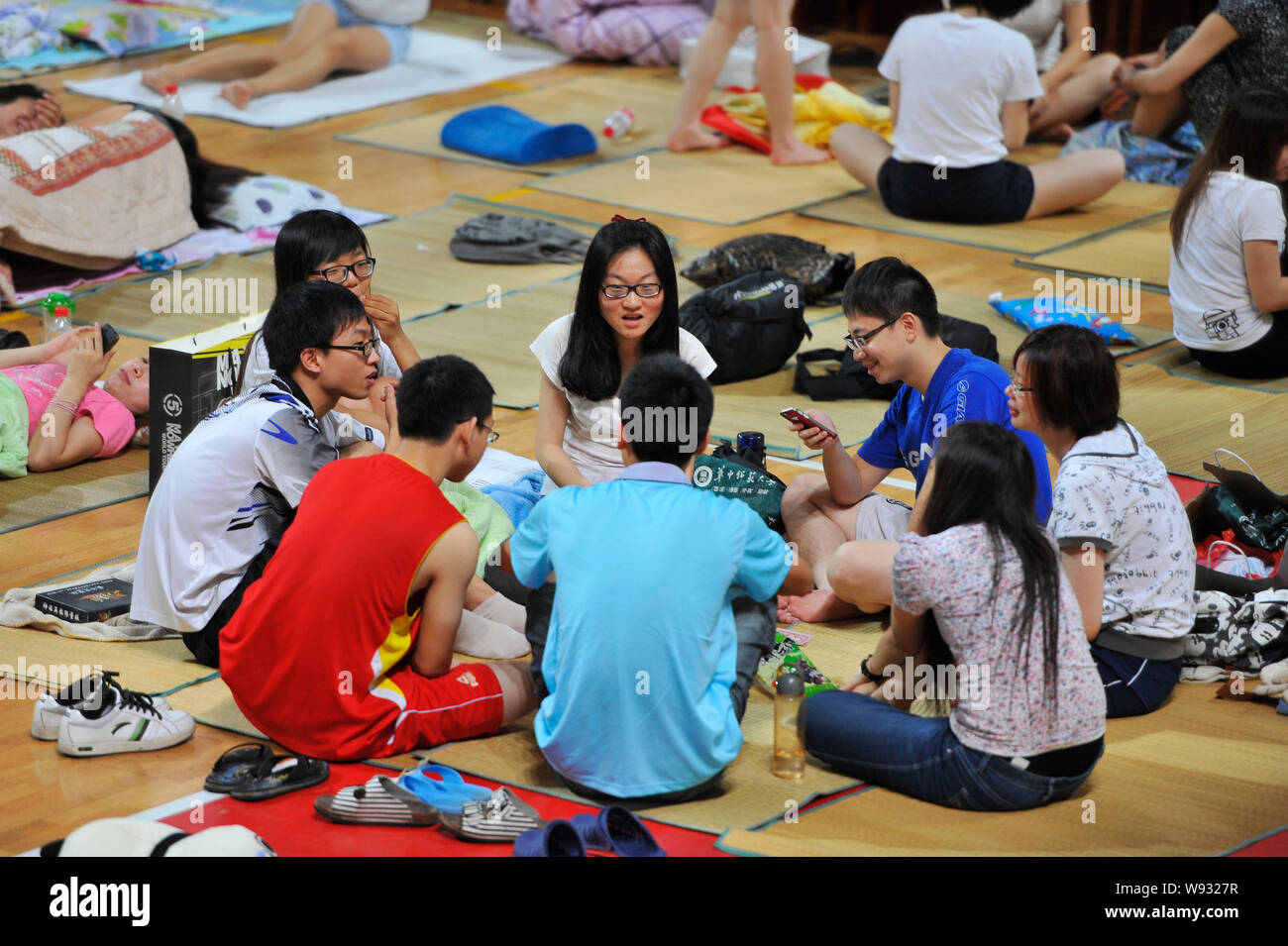 College students sitting on bamboo/straw mats at a air-conditioned ...