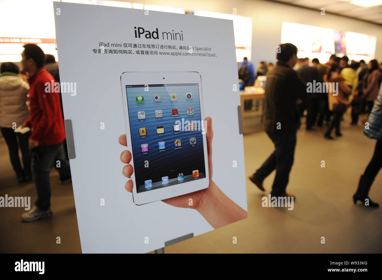 --FILE--Customers walk past an advertising poster of the iPad mini ...