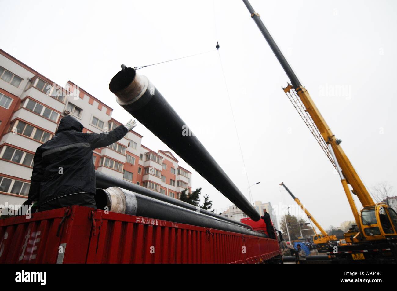 Chinese workers direct a crane vehicle to lift a new pipe at the ...