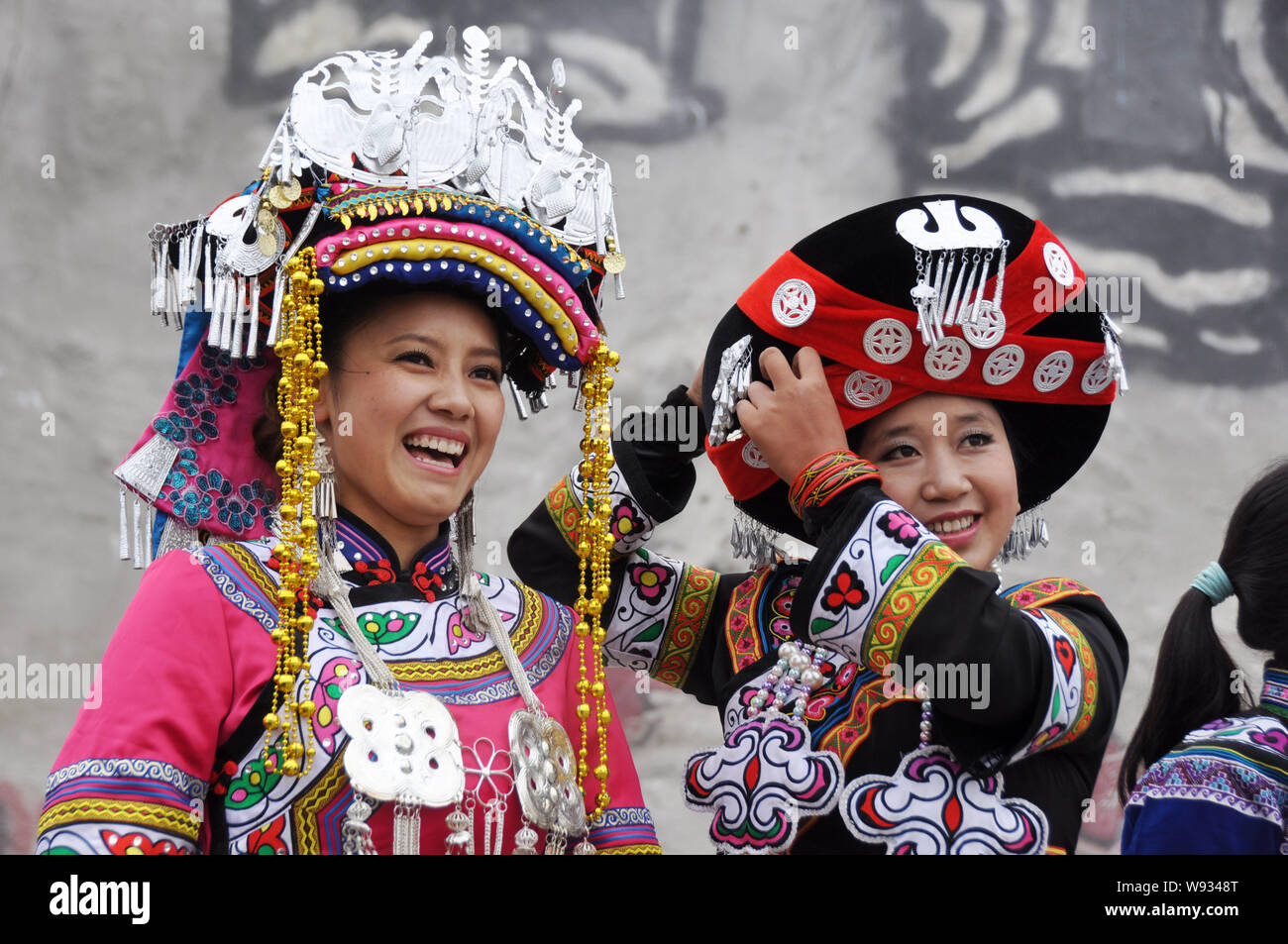 Chinese women of Yi ethnic minority dressed in traditional Yi costumes laugh during a ...