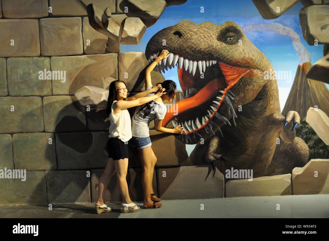 Chinese visitors pose to put their hands into a dinosaurs mouth for a ...